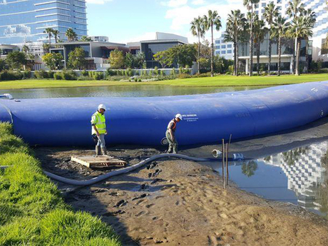Water filled inflatable flood barrier could be used in construction or ...